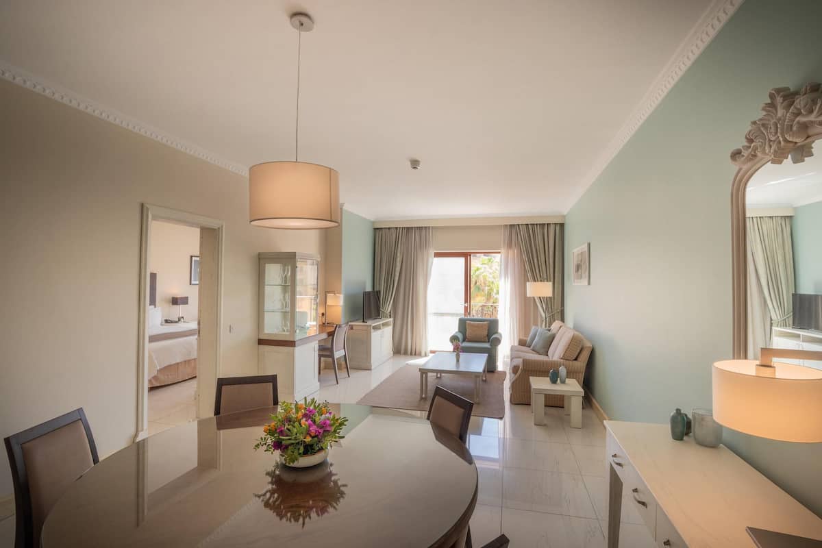 Quarto de hotel com área de refeições, sala de estar e cozinha.