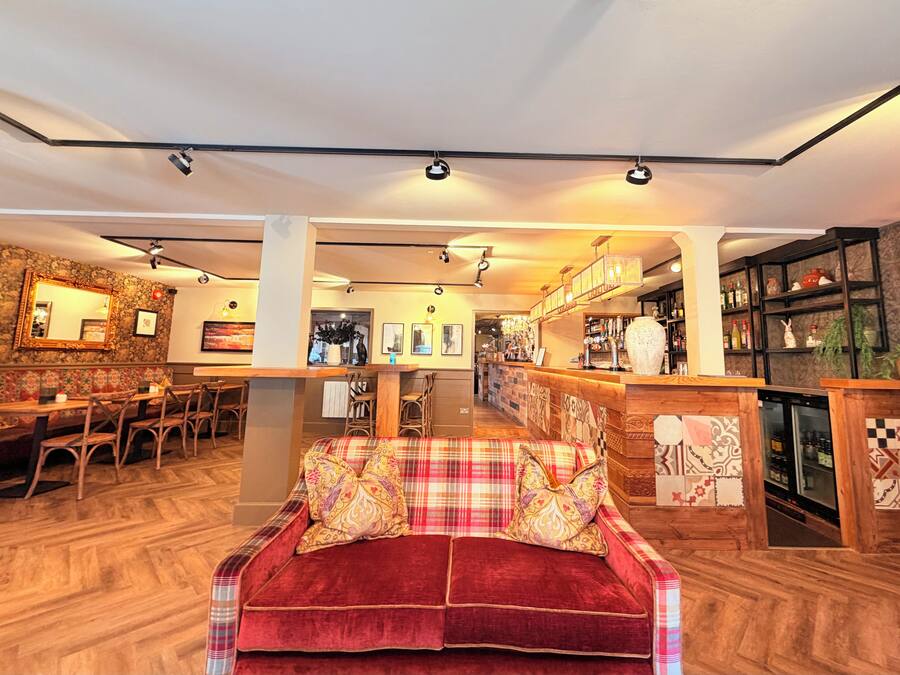 Um hall de hotel com área de bar, espaços de estar e lareira.