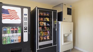 Máquina automática com design de bandeira americana, um dispensador de água e diversas opções de lanches.
