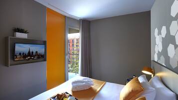 Quarto de hotel com cama, bandeja de café da manhã, televisão e vista para a cidade.