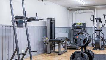 Uma academia com equipamentos de ginástica, um banco de musculação e esteira.
