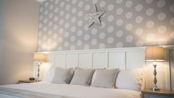 Uma cama bem arrumada com almofadas xadrez, uma decoração de estrela na parede e duas luminárias de cabeceira.