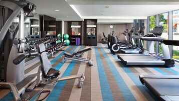 Uma academia moderna com diversos equipamentos de exercício, incluindo esteiras, elípticos e bancos de peso.