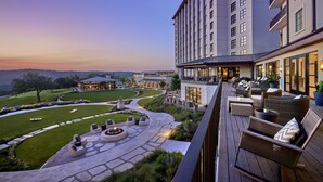 Um hotel com terraço no telhado, área de estar externa e gramado bem cuidado.