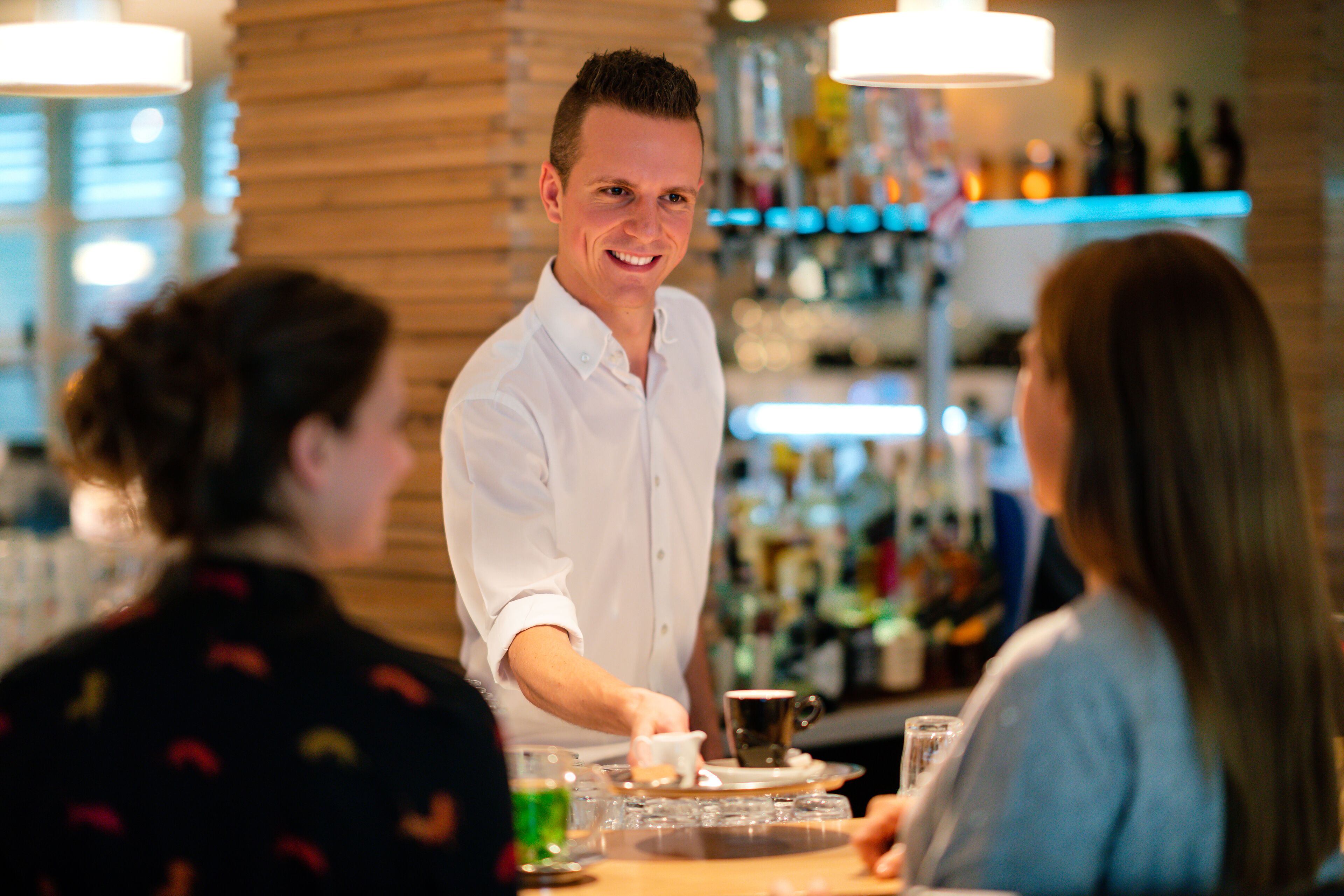 Um bar com um bartender servindo bebidas aos clientes.