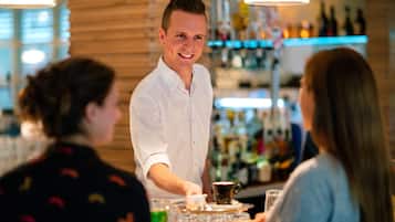Um bar com um bartender servindo bebidas aos clientes.