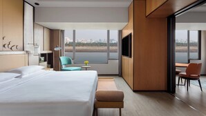 Quarto de hotel moderno com uma cama grande, uma escrivaninha, uma cadeira e uma televisão.