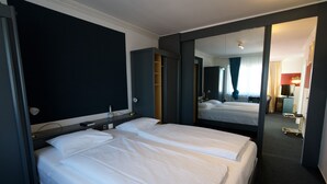 Quarto de hotel com duas camas, um espelho grande e um guarda-roupa.