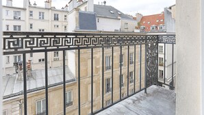 Varanda com guarda-corpo de ferro forjado decorativo, vista para uma fileira de edifícios com estilos arquitetônicos variados e céu limpo.
