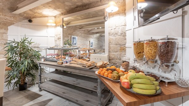 Um buffet com diversos alimentos, uma mesa de madeira e uma parede de pedra.