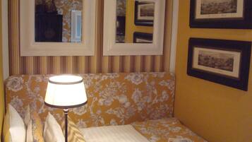 Quarto com sofá floral, uma luminária e três quadros na parede.
