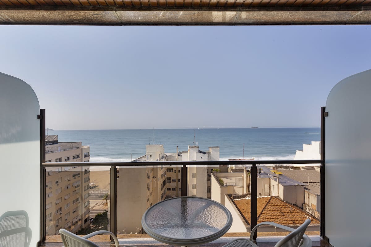 Varanda com vista para o mar, uma cadeira e uma mesa.