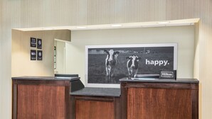 Balcão de recepção de hotel com uma grande fotografia a preto e branco de vacas e a palavra 