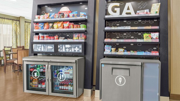 Uma área de distribuição automática com lanches, bebidas e um refrigerador.