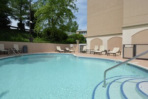 Piscina com espreguiçadeiras e um terraço coberto.