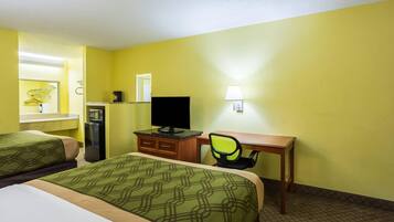 Quarto de hotel com duas camas, uma escrivaninha, televisão, abajur e espelho.