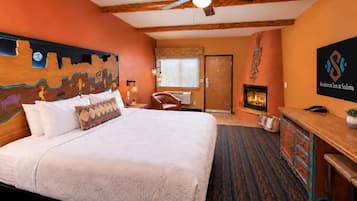 Quarto de hotel com uma cama grande, escrivaninha, lareira e ventoinha no teto.