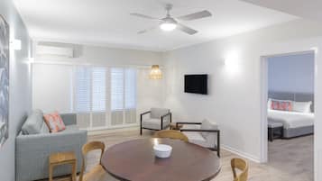 Uma sala de estar moderna com uma mesa de madeira redonda, sofás cinzentos e um ventilador de teto.