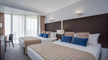 Quarto de hotel com duas camas, uma escrivaninha e uma cadeira.