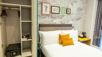 Quarto de hotel com cama, guarda-roupa e parede decorada com quadros.