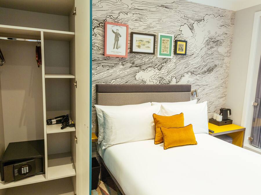 Quarto de hotel com cama, guarda-roupa e parede decorada com quadros.