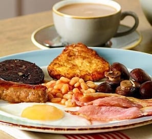 Prato de comida de café da manhã com ovos, linguiça, feijão, cogumelos e torradas.