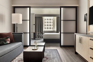 Quarto de hotel moderno com sofá, mesa de centro com um vaso, cama, escrivaninha e televisão.