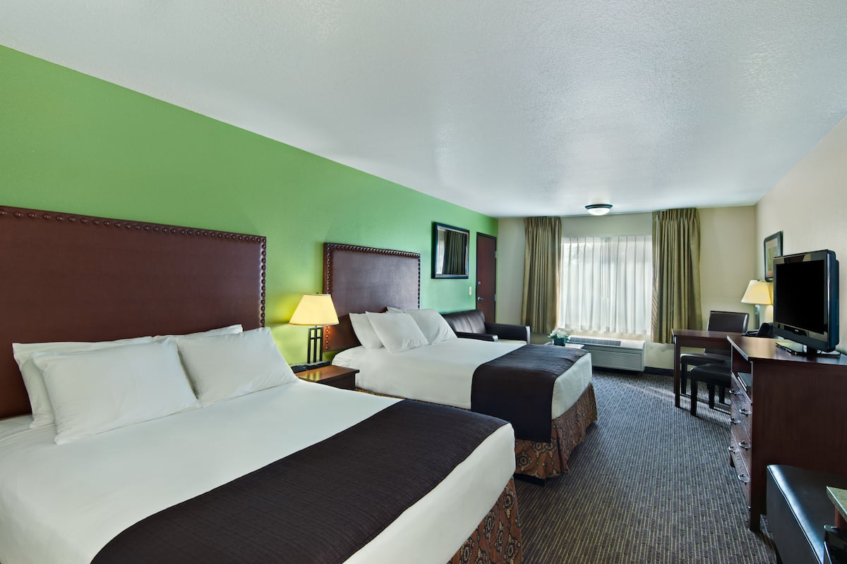 Quarto de hotel com duas camas, televisão, escrivaninha e uma cadeira.
