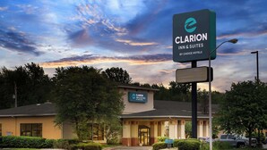 Edifício do Clarion Inn & Suites com céu claro e árvores ao fundo.