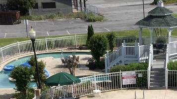 Área da piscina com um gazebo, cadeiras de descanso e aviso de supervisão de adultos necessária.