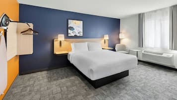 Quarto de hotel com cama, mesas de cabeceira, luminárias, um quadro na parede e uma janela com cortinas.