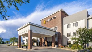 Um hotel com um letreiro grande da 'La Quinta', entrada coberta e estacionamento.