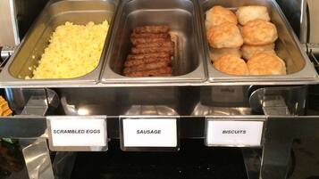 Buffet com seções identificadas para ovos mexidos, salsicha e biscoitos.
