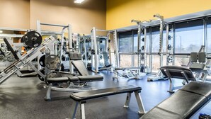 Uma academia com diversos equipamentos de exercícios, bancos e aparelhos de musculação.
