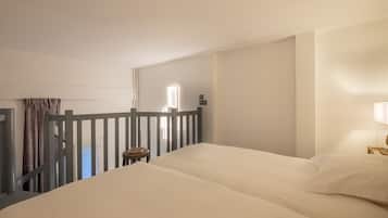 Quarto de hotel com cama, mesa de cabeceira, abajur e vista para o exterior.