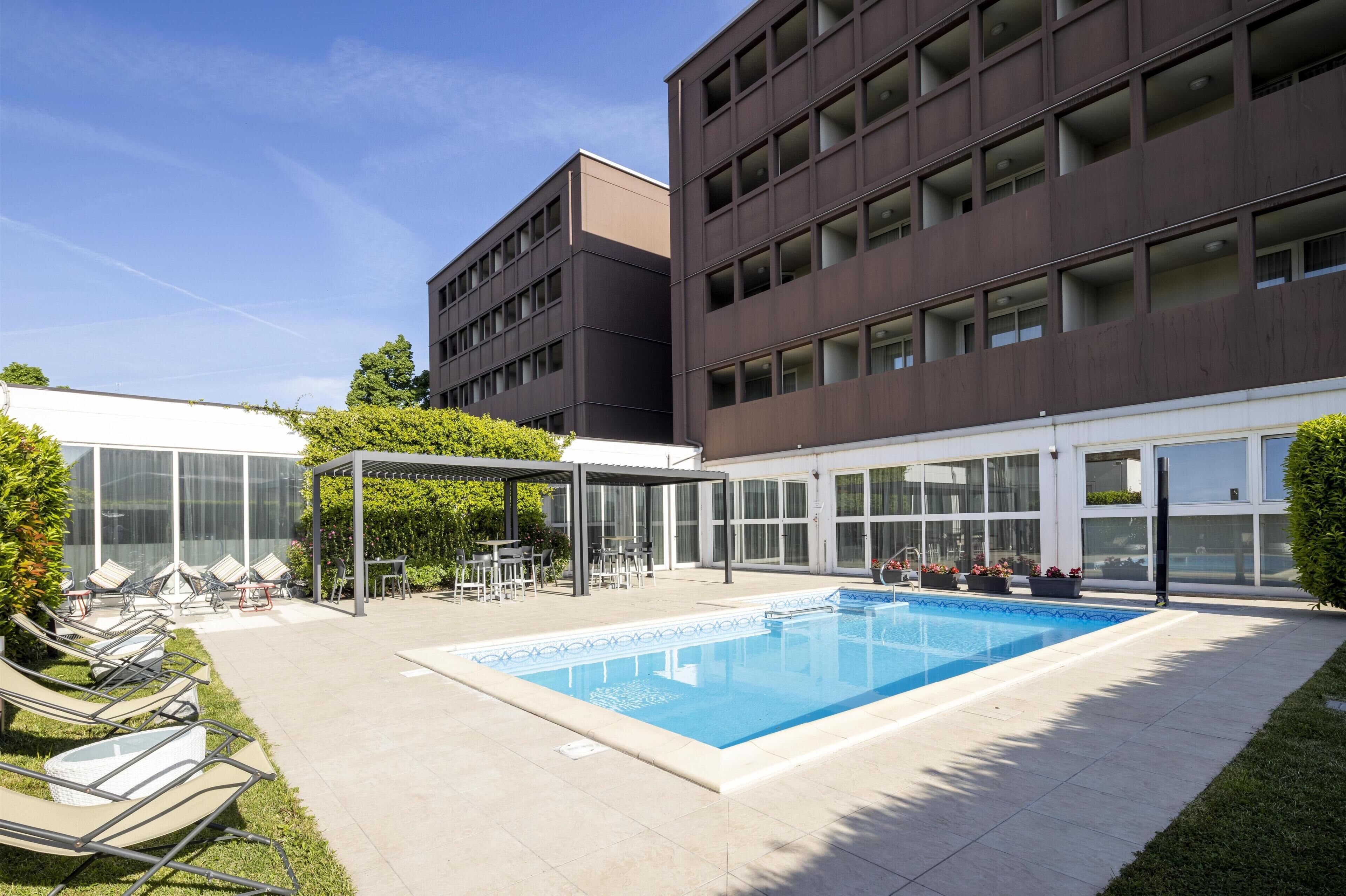 Um edifício moderno com piscina, área de estar ao ar livre e um pátio coberto.