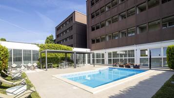 Um edifício moderno com piscina, área de estar ao ar livre e um pátio coberto.