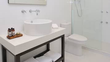 Uma casa de banho moderna com uma pia branca, espelho e cabine de duche em vidro.