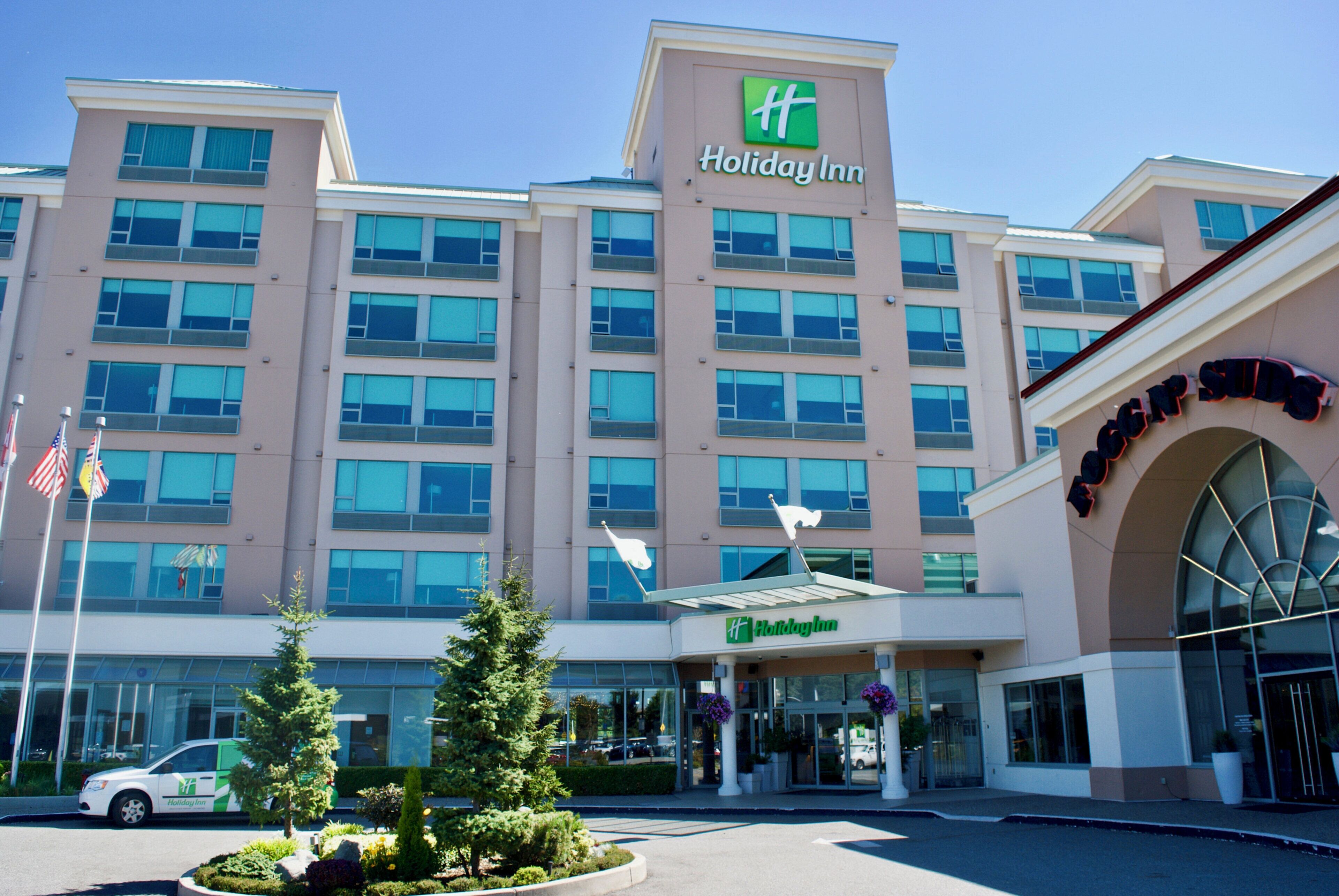 Um hotel Holiday Inn com fachada moderna, várias janelas e uma bandeira no topo.