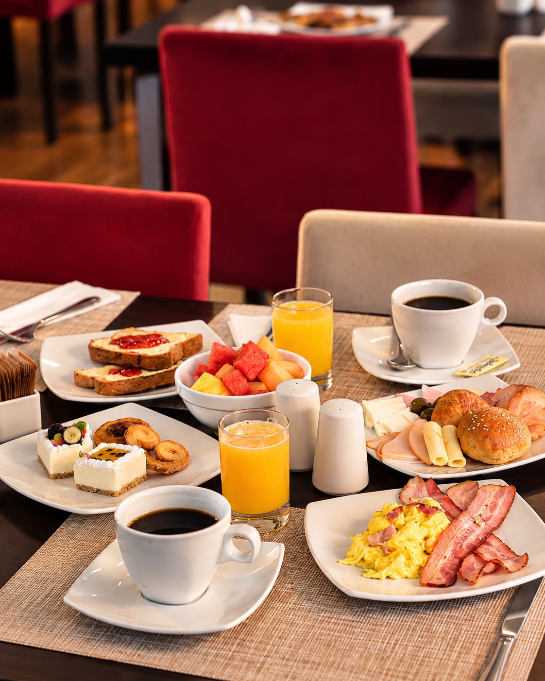 Um buffet de café da manhã com diversos pratos, incluindo torradas, frutas, ovos e bacon.