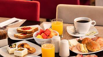 Um buffet de café da manhã com diversos pratos, incluindo torradas, frutas, ovos e bacon.