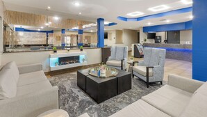 Um lobby moderno com balcão de recepção, área de estar e lareira.