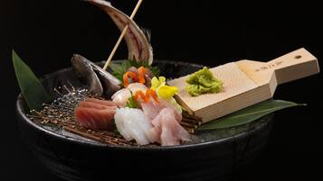 Uma tigela de sashimi com diferentes tipos de peixe, acompanhamentos e uma tábua de servir de madeira.