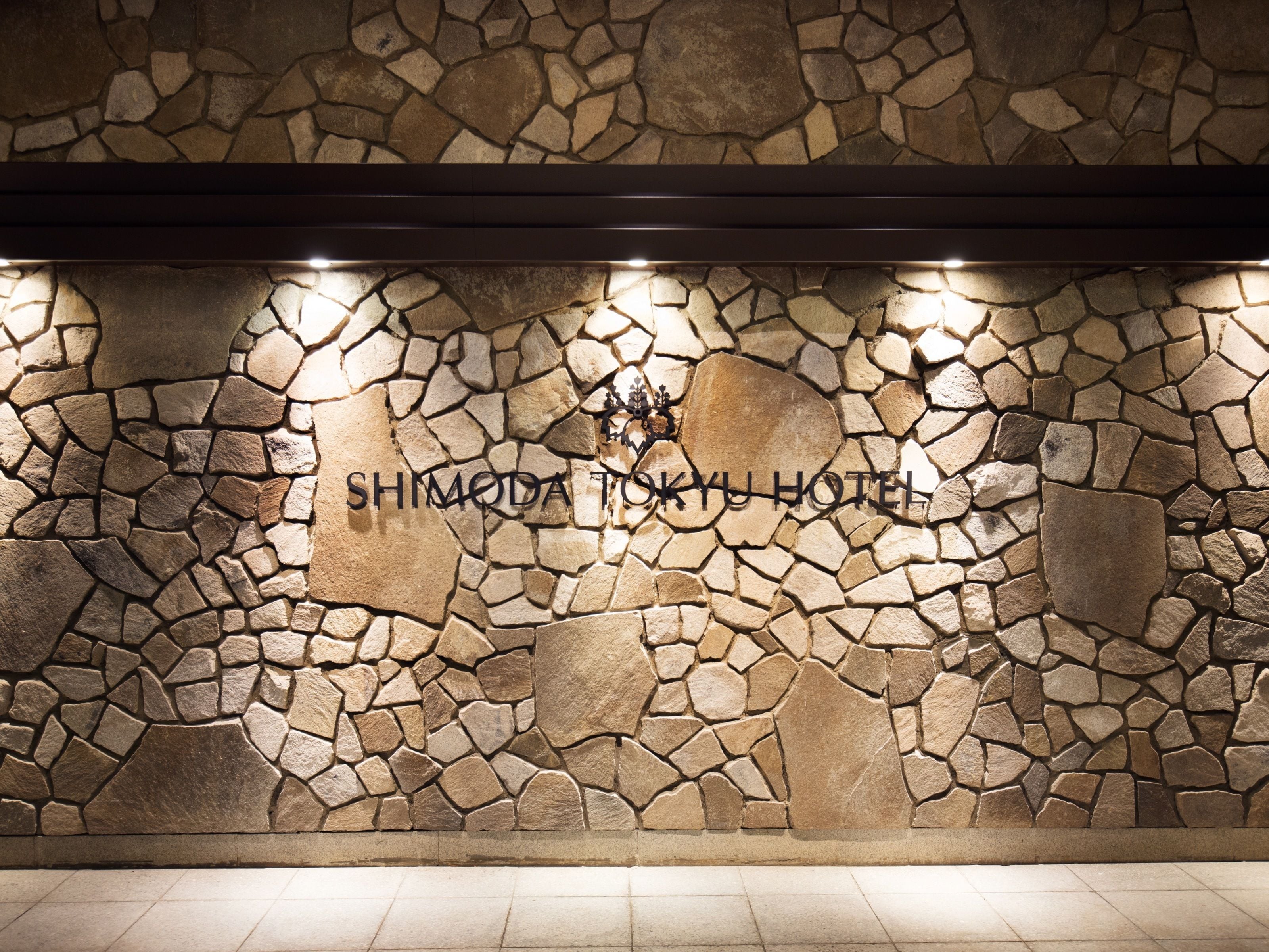 Paredes de pedra com o texto "SHIMODA TOKYU HOTEL" no centro.
