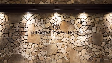 Paredes de pedra com o texto "SHIMODA TOKYU HOTEL" no centro.