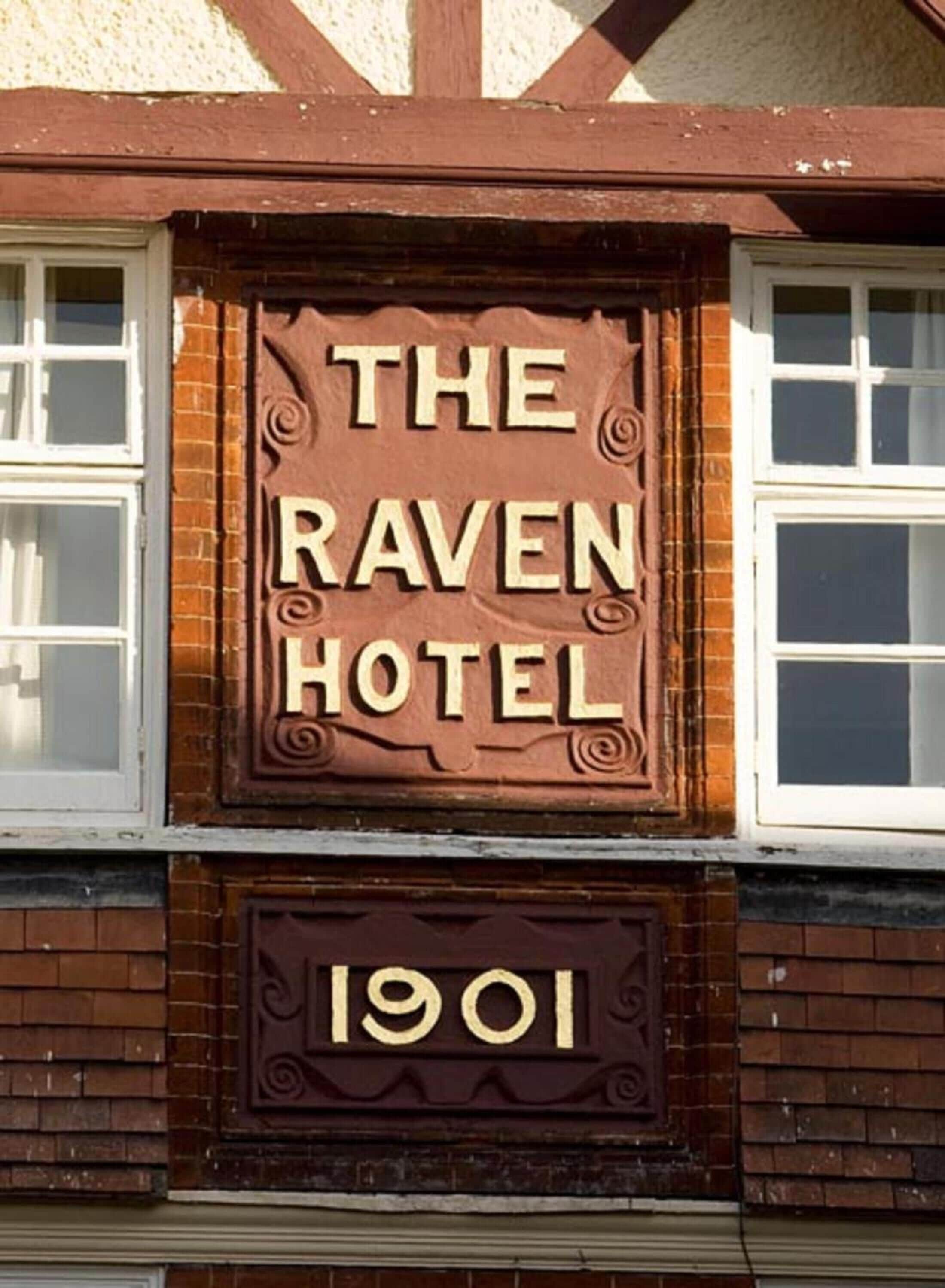 Placa do hotel 'The Raven Hotel' com o ano '1901' abaixo.