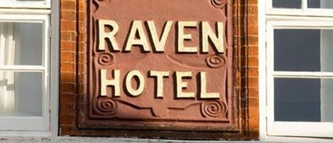 Placa do hotel 'The Raven Hotel' com o ano '1901' abaixo.
