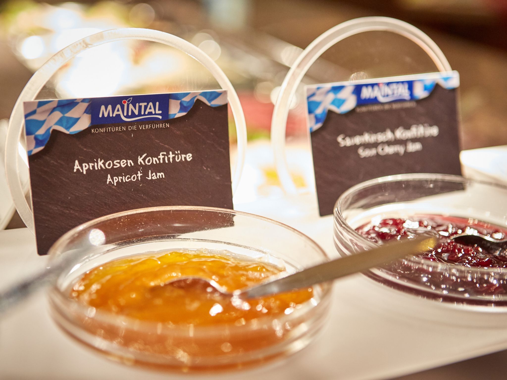 Duas tigelas identificadas com doce de damasco e doce de cereja sobre uma mesa.