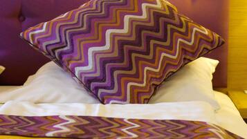 Uma cama com almofada estampada e manta listrada.