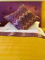 Uma cama com almofada estampada e manta listrada.